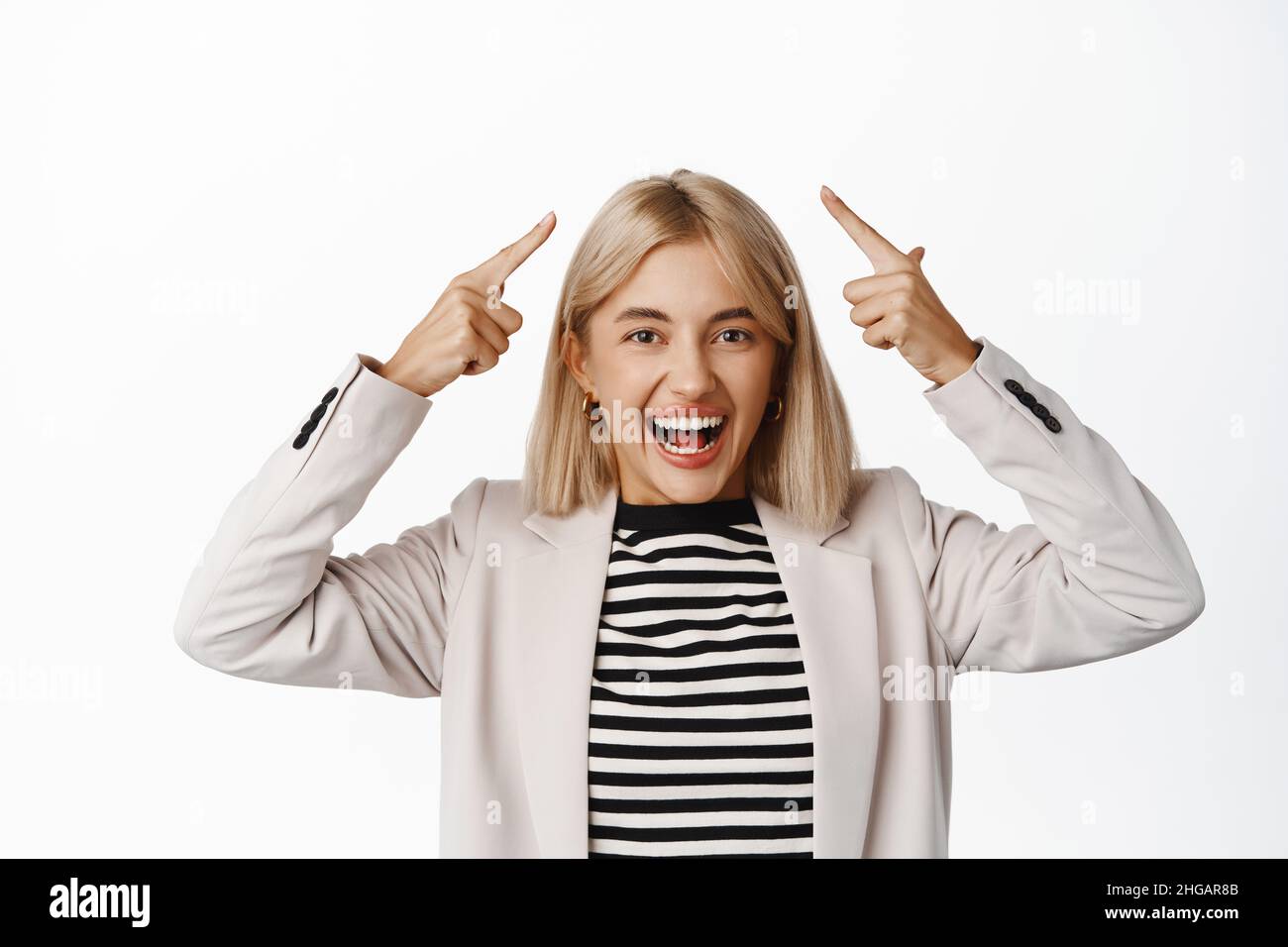 Happy smiling blond woman pointing under her head, showing promo offer ...