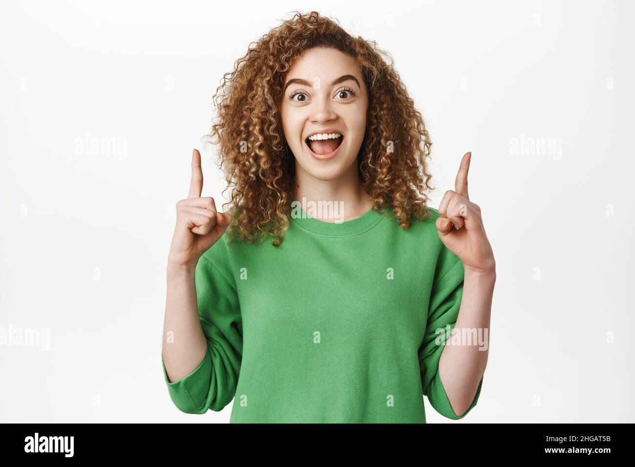 Hey take a look. Excited smiling young female model showing promo offer ...