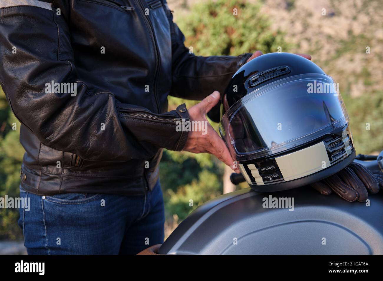A unrecognizable man putting helmet on motorcycle Stock Photo - Alamy
