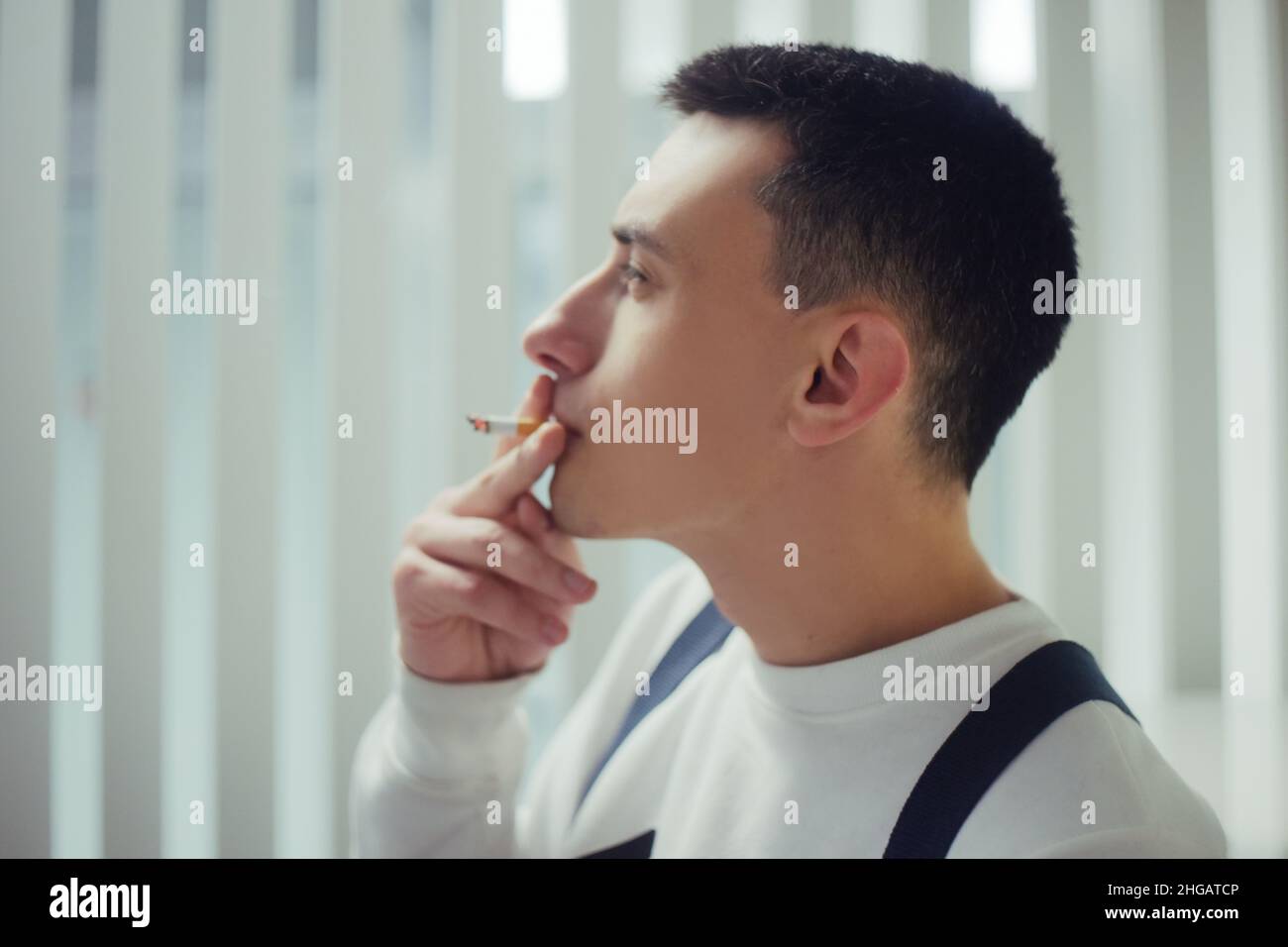 Portrait of a man smoking in a smoking cubicle. Cigarette smoking area ...