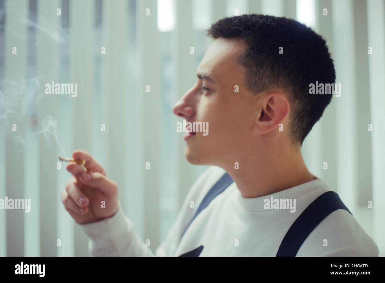 Portrait of a man smoking in a smoking cubicle. Cigarette smoking area ...