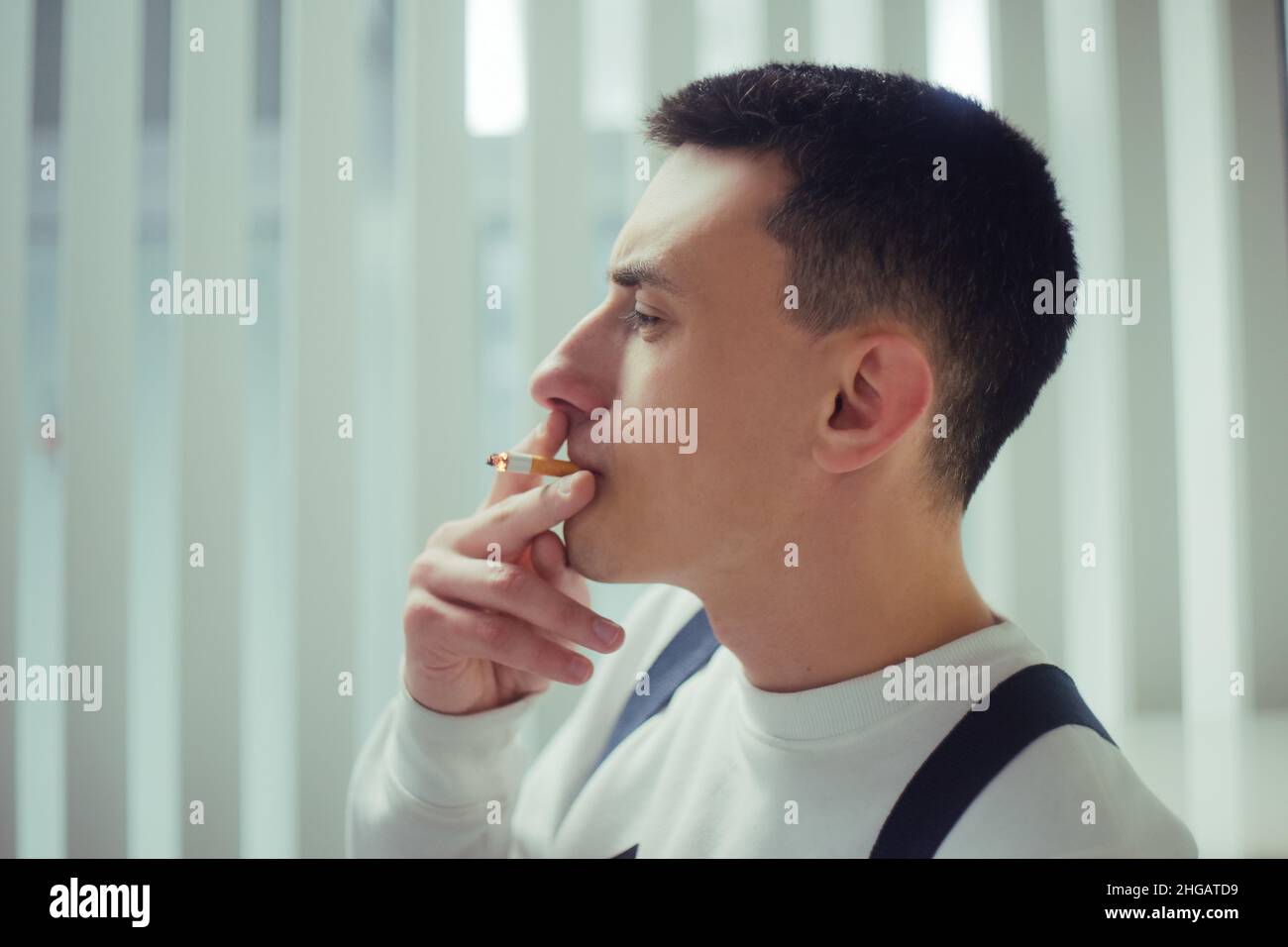 Portrait of a man smoking in a smoking cubicle. Cigarette smoking area ...