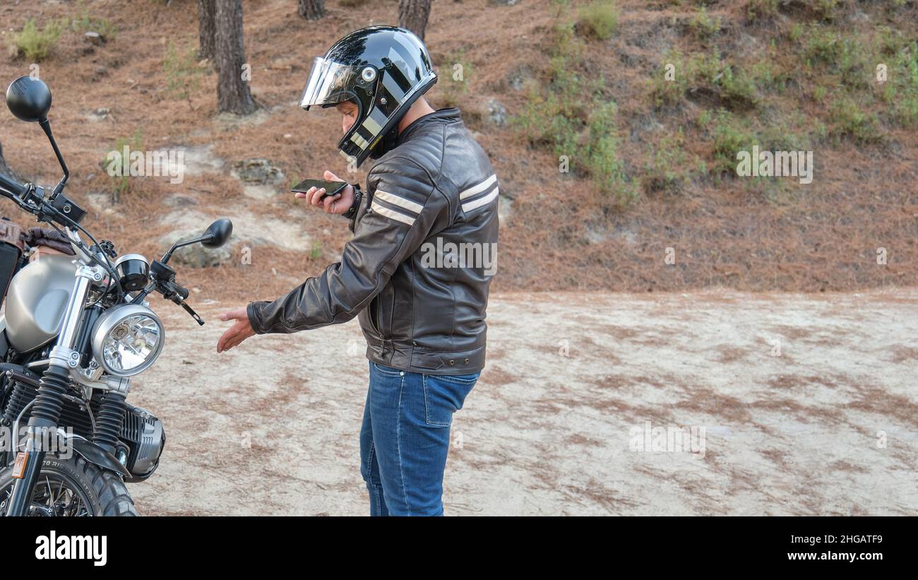 Biker talking on the phone to the insurance of his motorcycle after ...