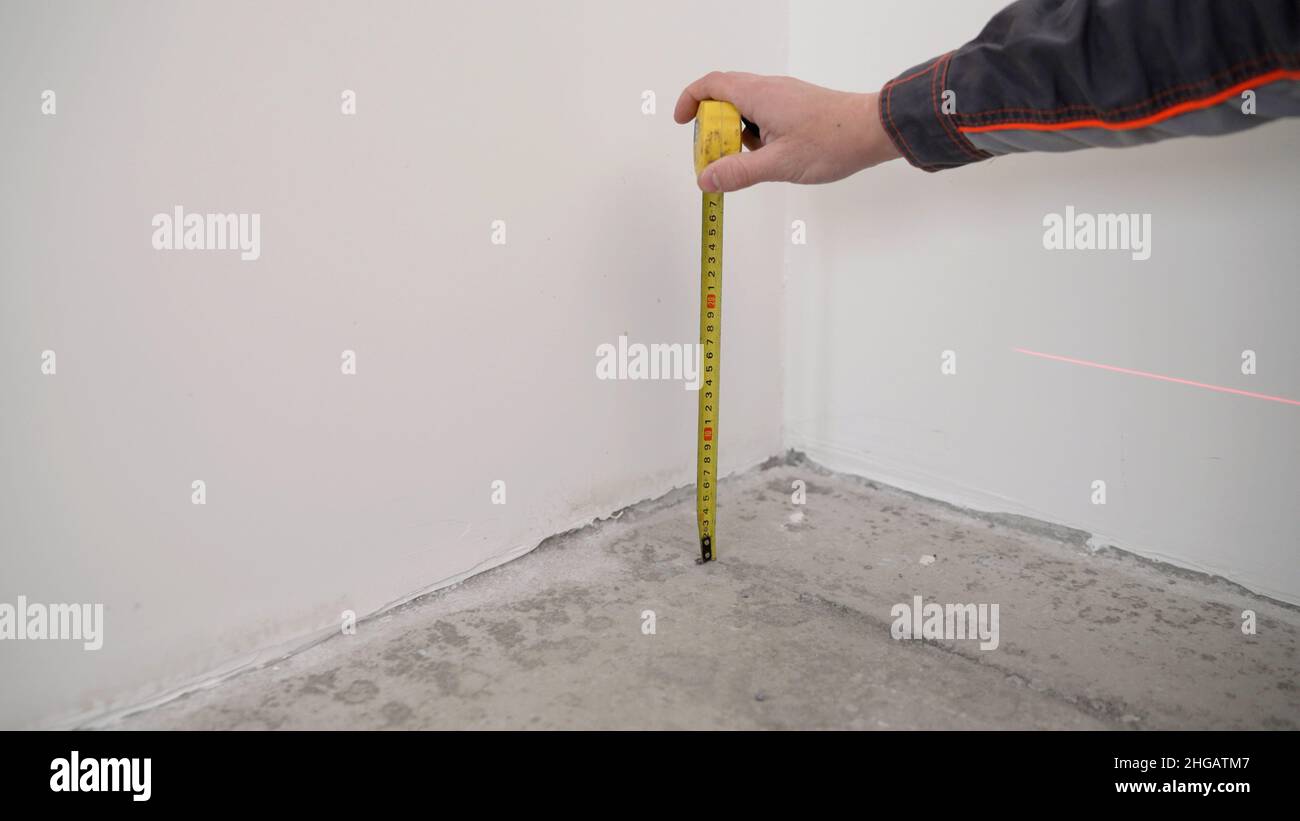 Checking the floor level with a ruler. A worker inspector checks the ...