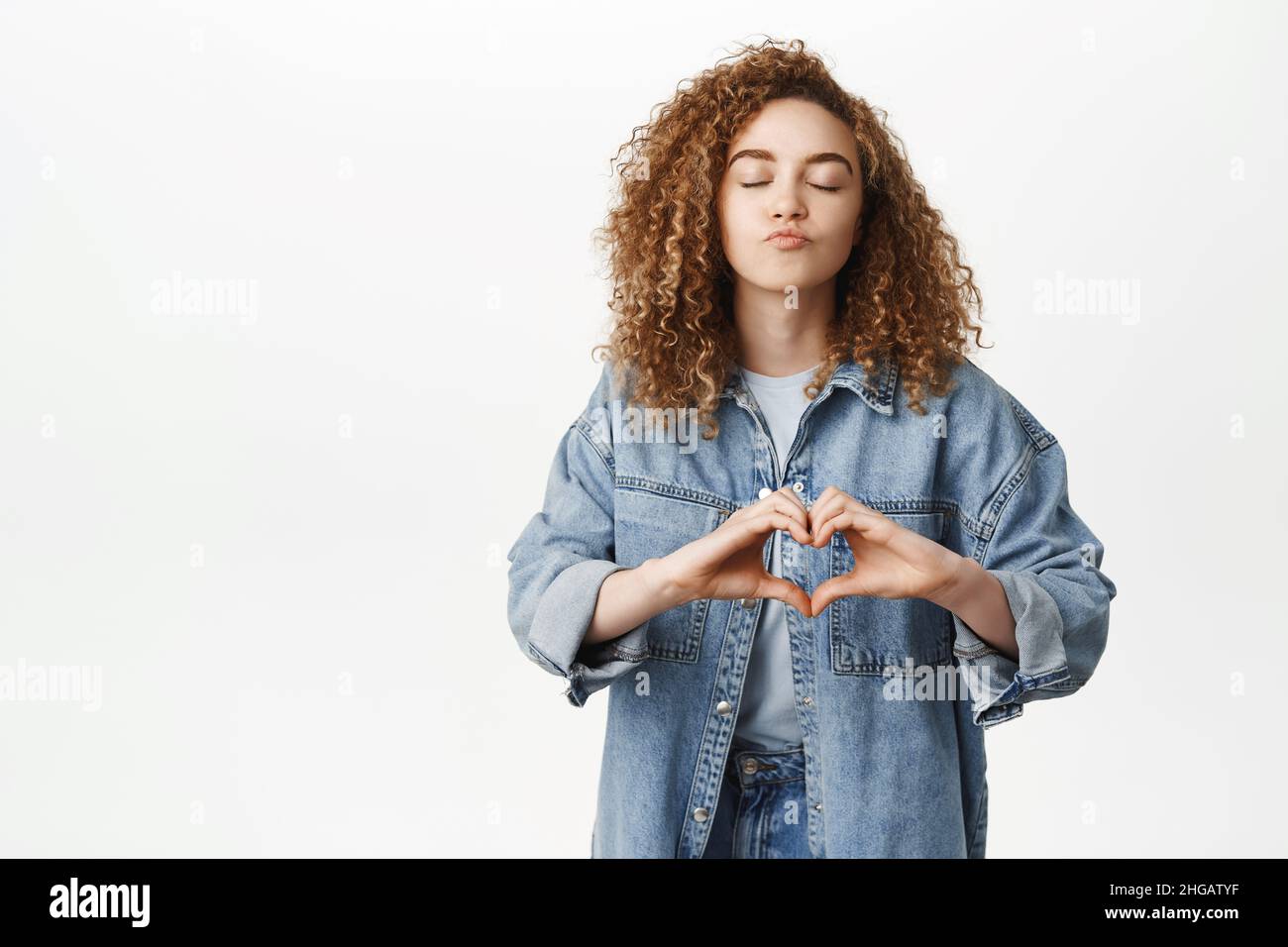 Portrait of smiling curly girl, stylish girlfriend shows heart, love ...