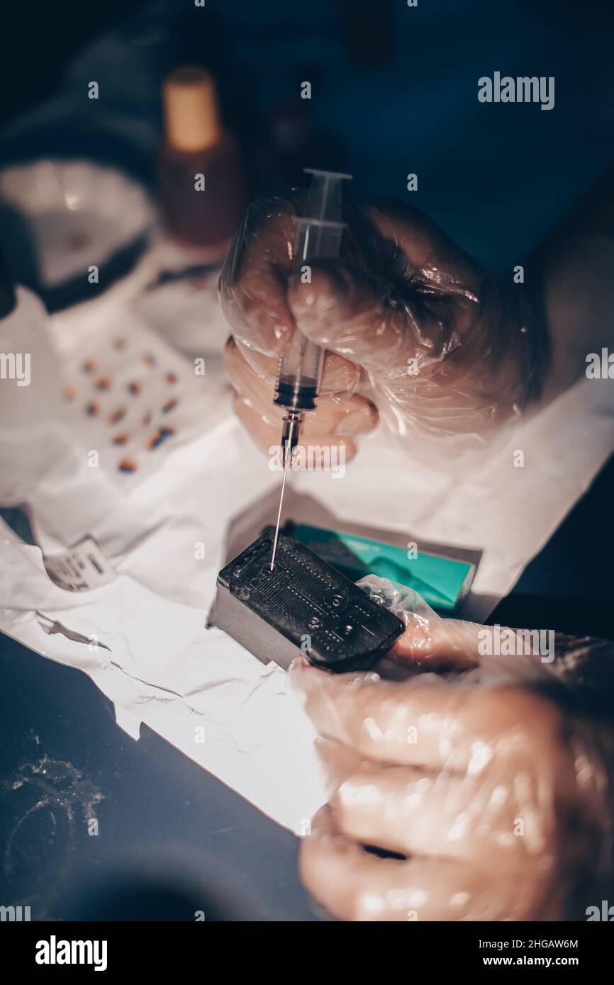Male hands refill printer cartridge. The guy makes holes in the ...