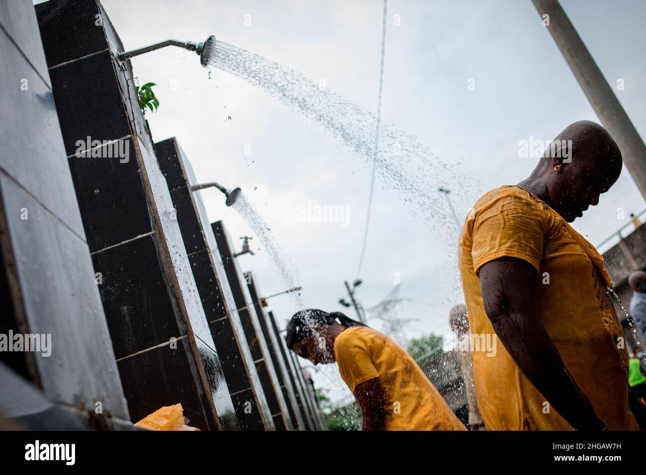 Two women are seen performing a religious ritual by bathing their ...