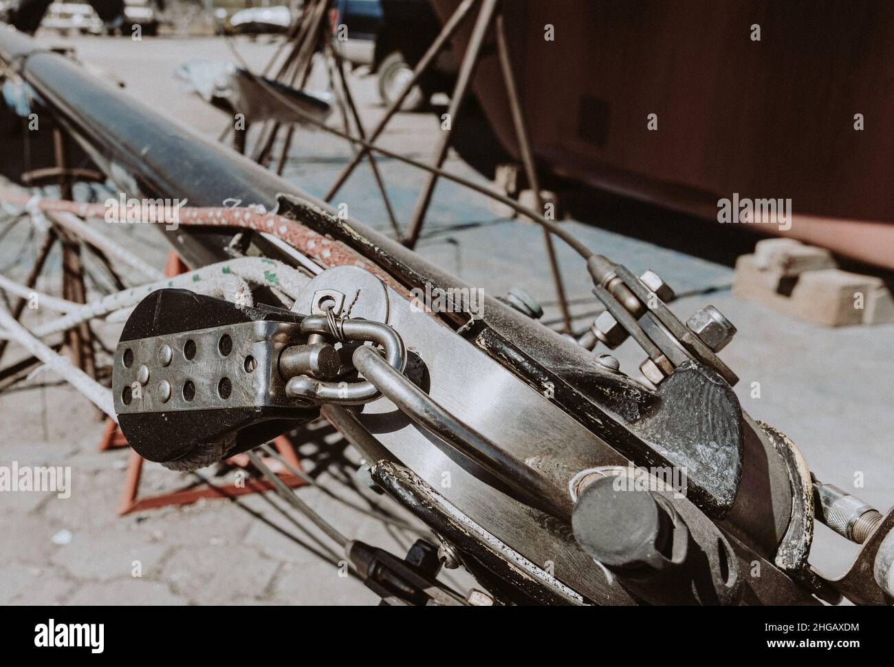 A mast with block and tackle and rigging lying on the ground next to ...
