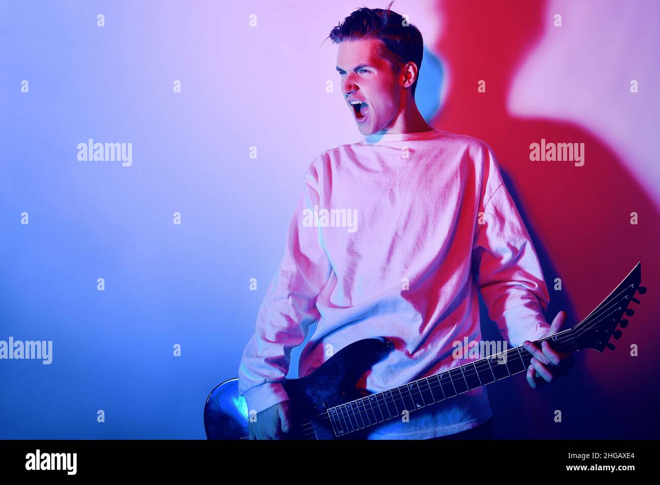 Portrait of young man artist singing, screaming, playing electric ...