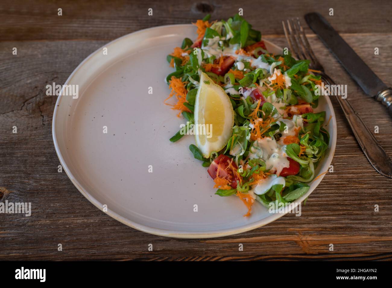 Mixed salad served as a side dish on a half full plate Stock Photo - Alamy