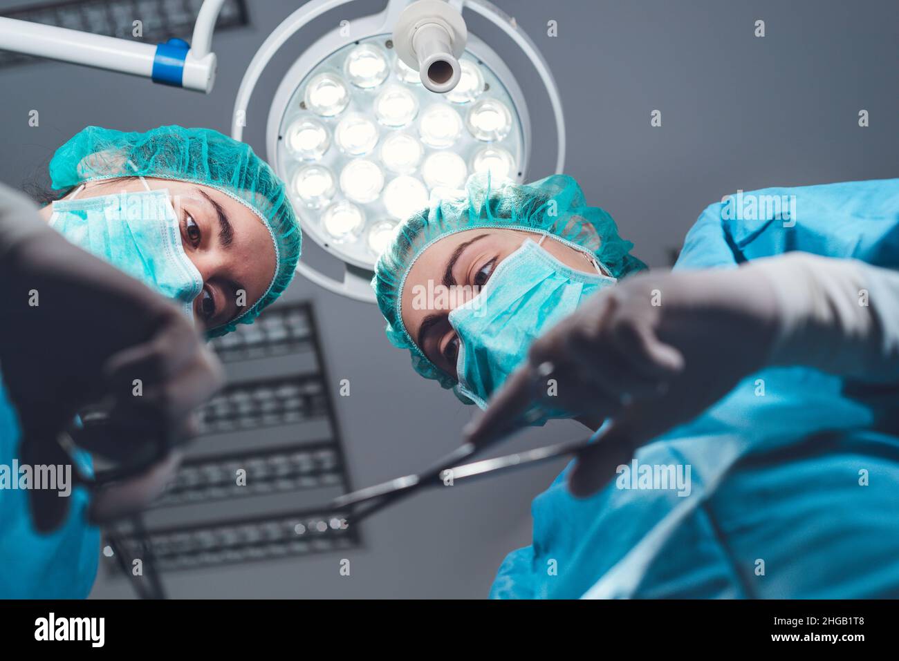From below female surgeons in medical uniform using professional tools ...