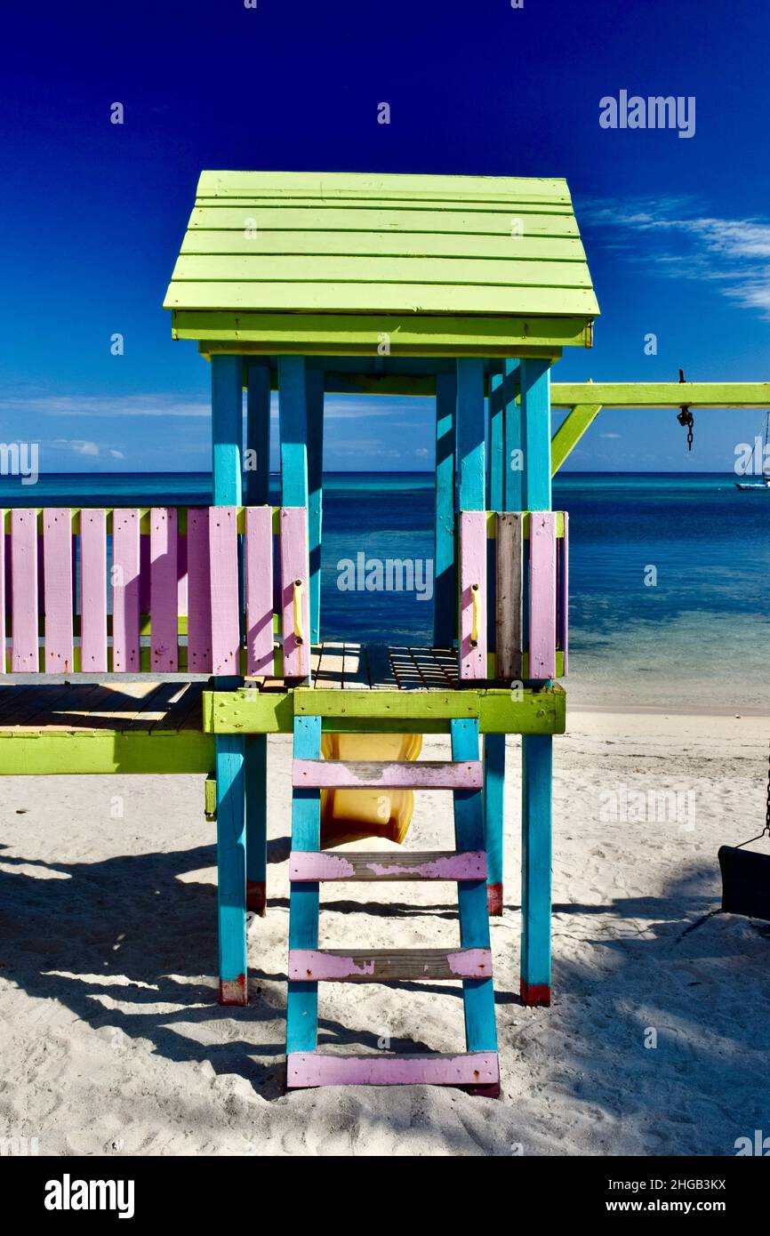 A pastel-colored play set on the beach overlooking the clear, blue ...