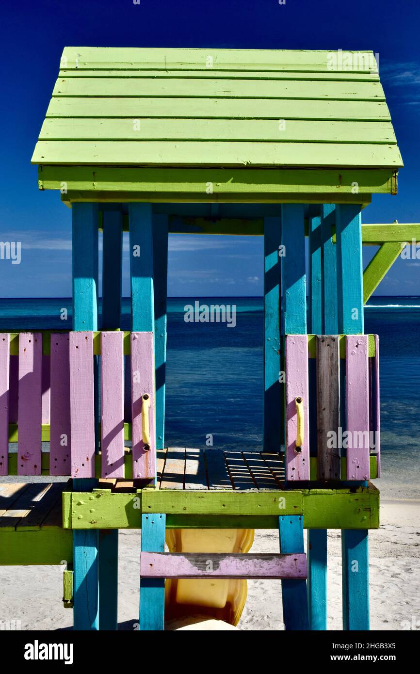 A pastel-colored play set on the beach overlooking the clear, blue ...