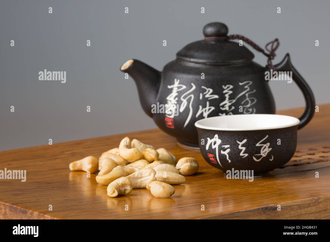 Traditional Asian tea cup and teapot. Service and cashew nuts on a ...