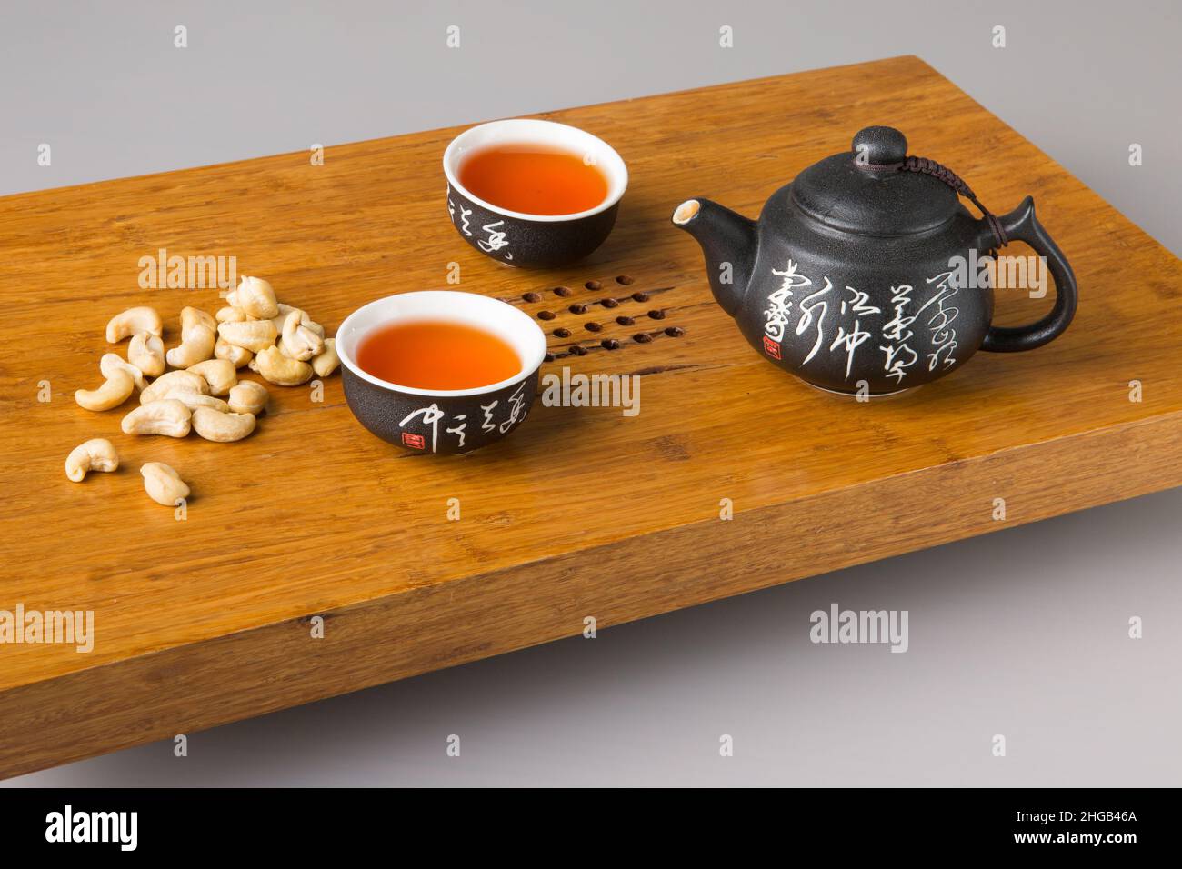 Two traditional Asian tea cups and a teapot. Service and cashew nuts on ...