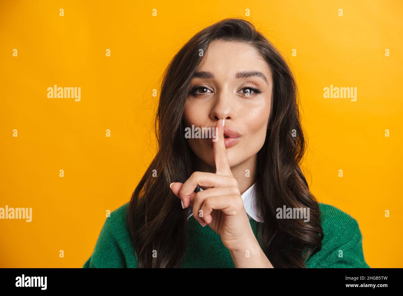 Portrait of a smiling casual woman standing over yellow background ...