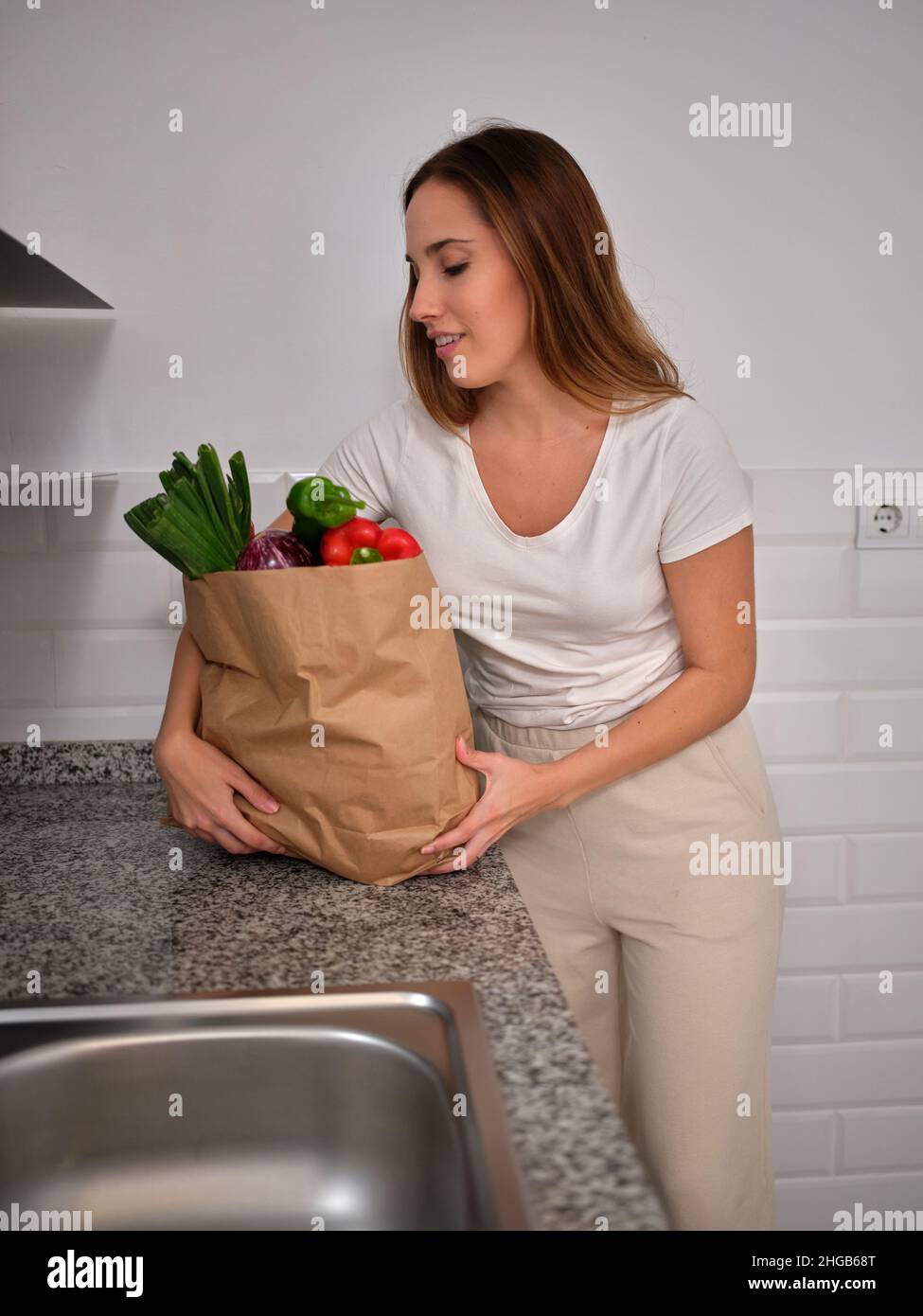 woman leaving the shopping bag in the kitchen after coming back from ...