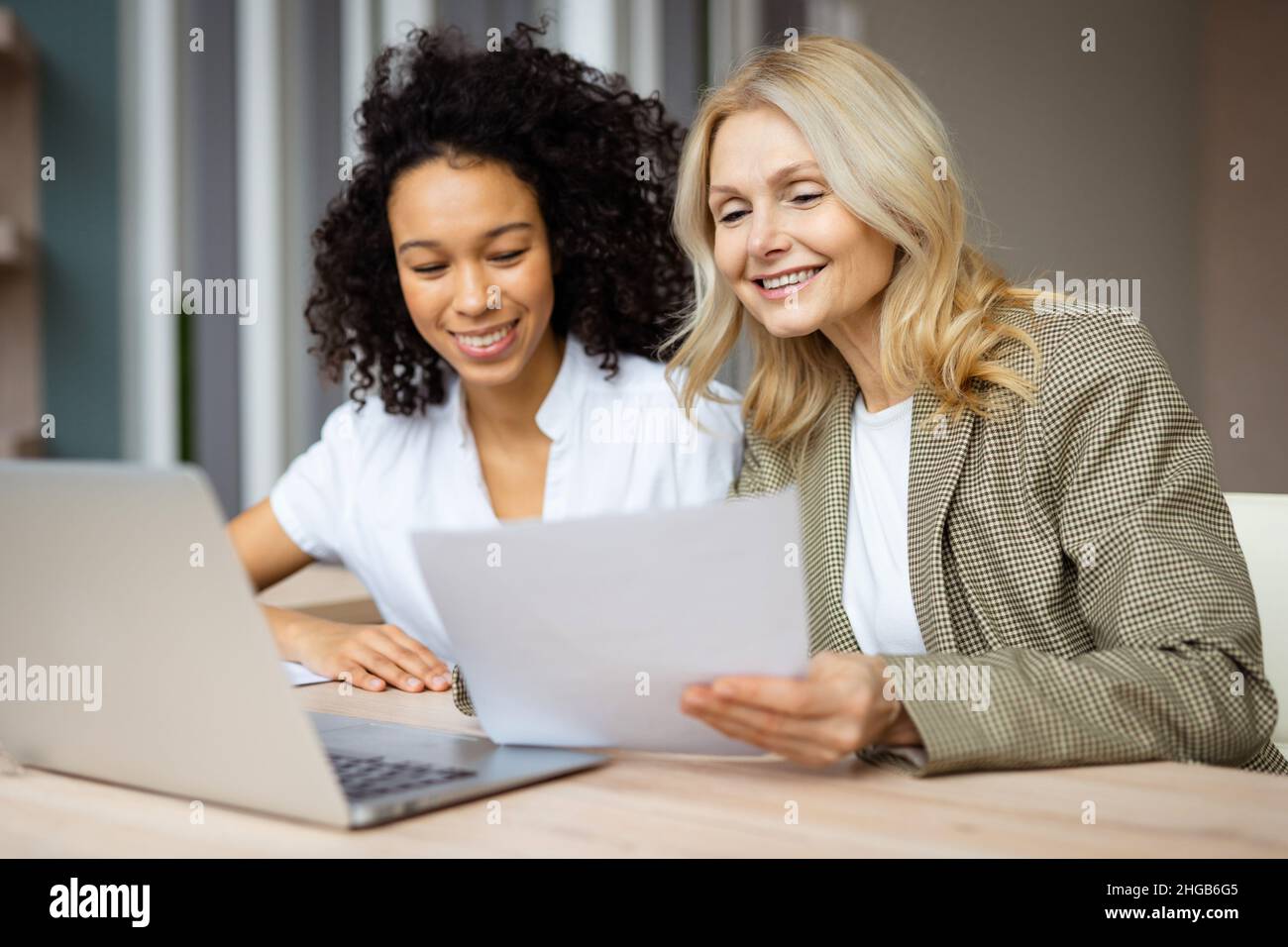 Beautiful adult businesswomen with elegant dress sitting at computer ...