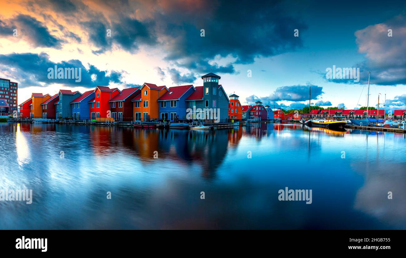Port in Groningen in the Netherlands. Boats, houses and beautiful sky at sunrise reflected in ...