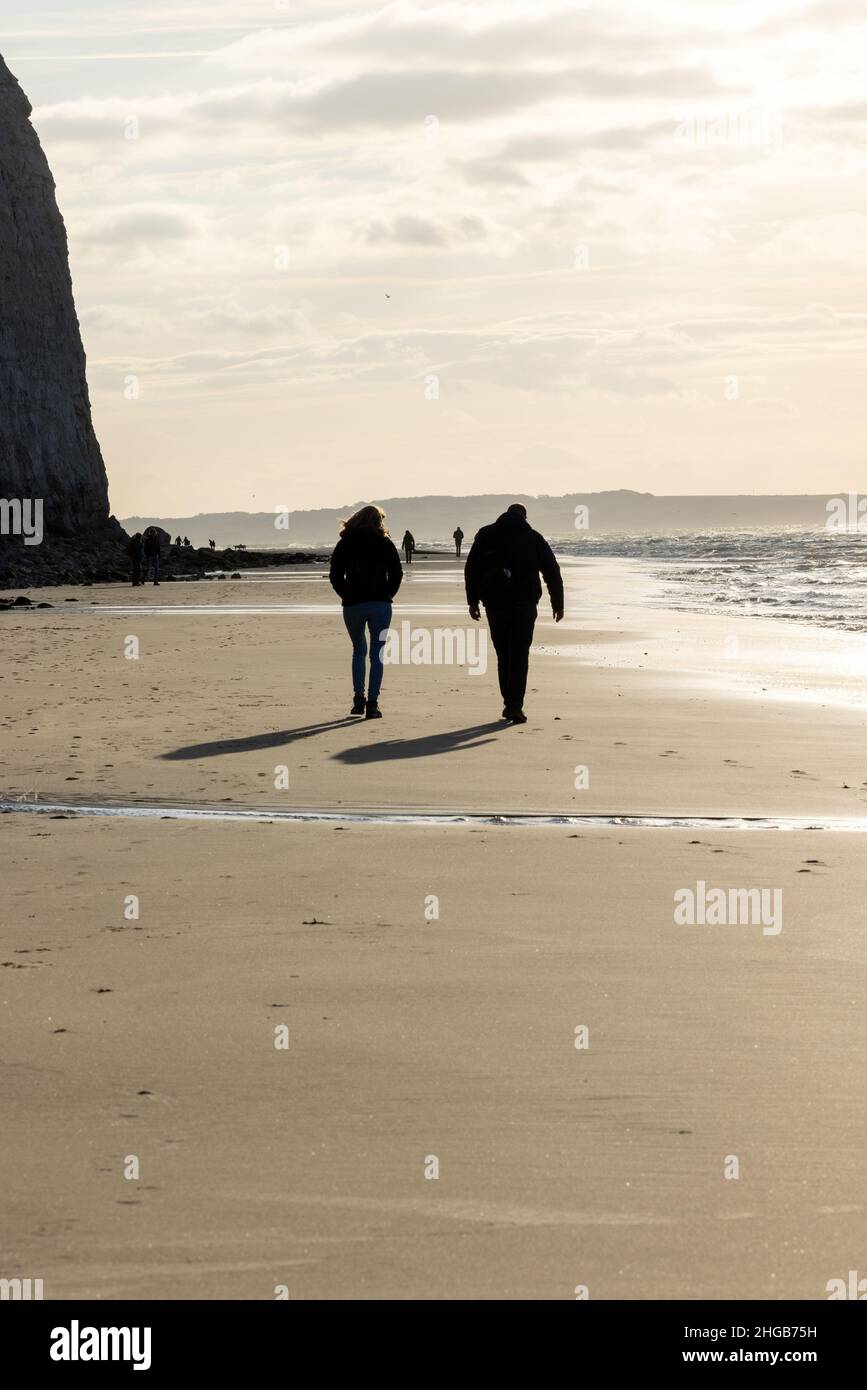 Two People Walking On The Beach In The Sunset
