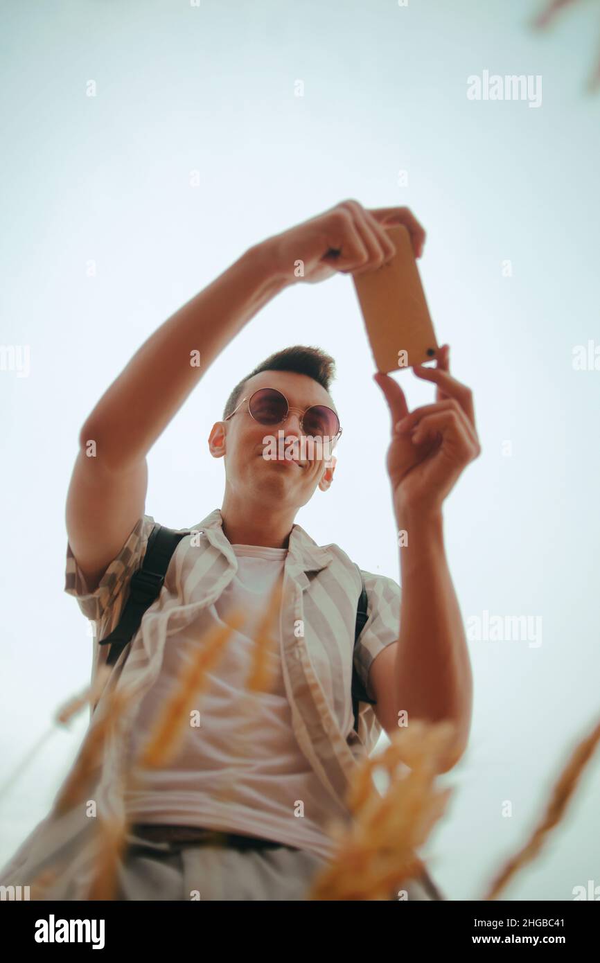 Photo of a man from below taking a photo of the field on his smartphone ...