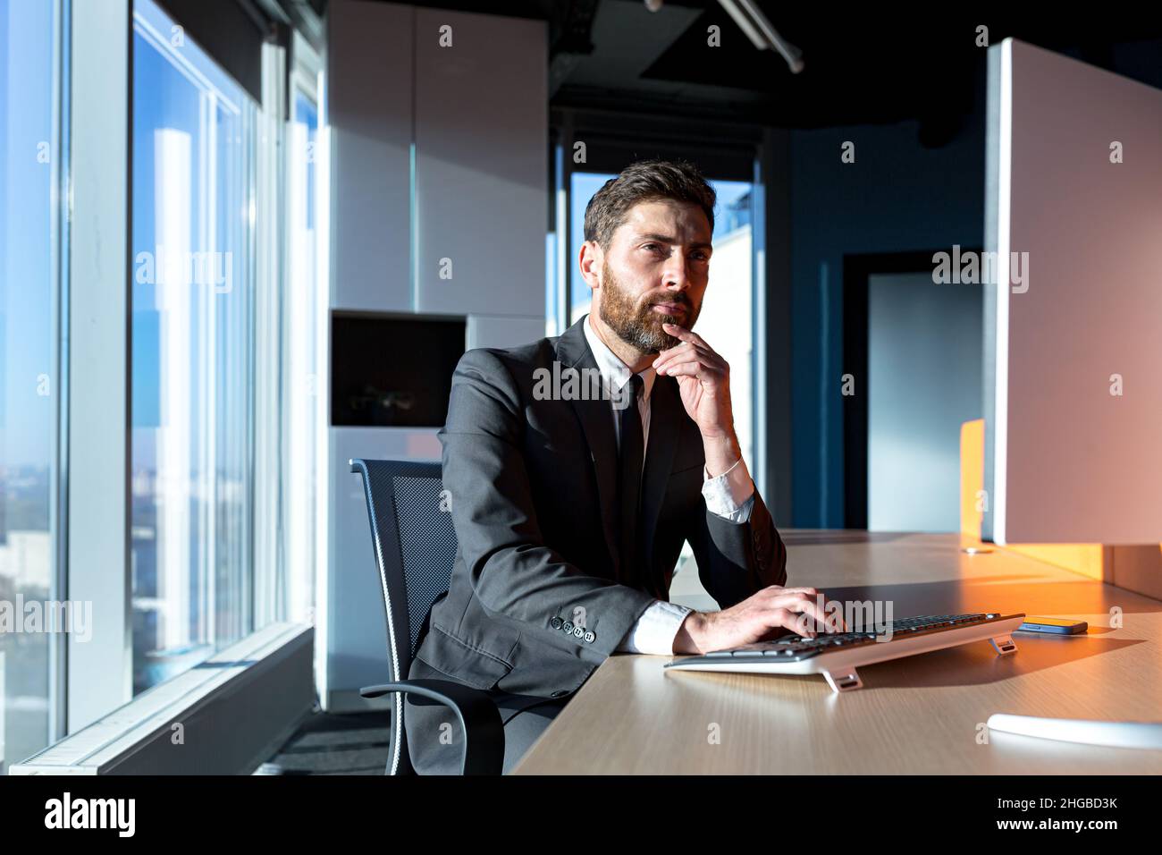 thinking male businessman working at computer in modern office by the ...