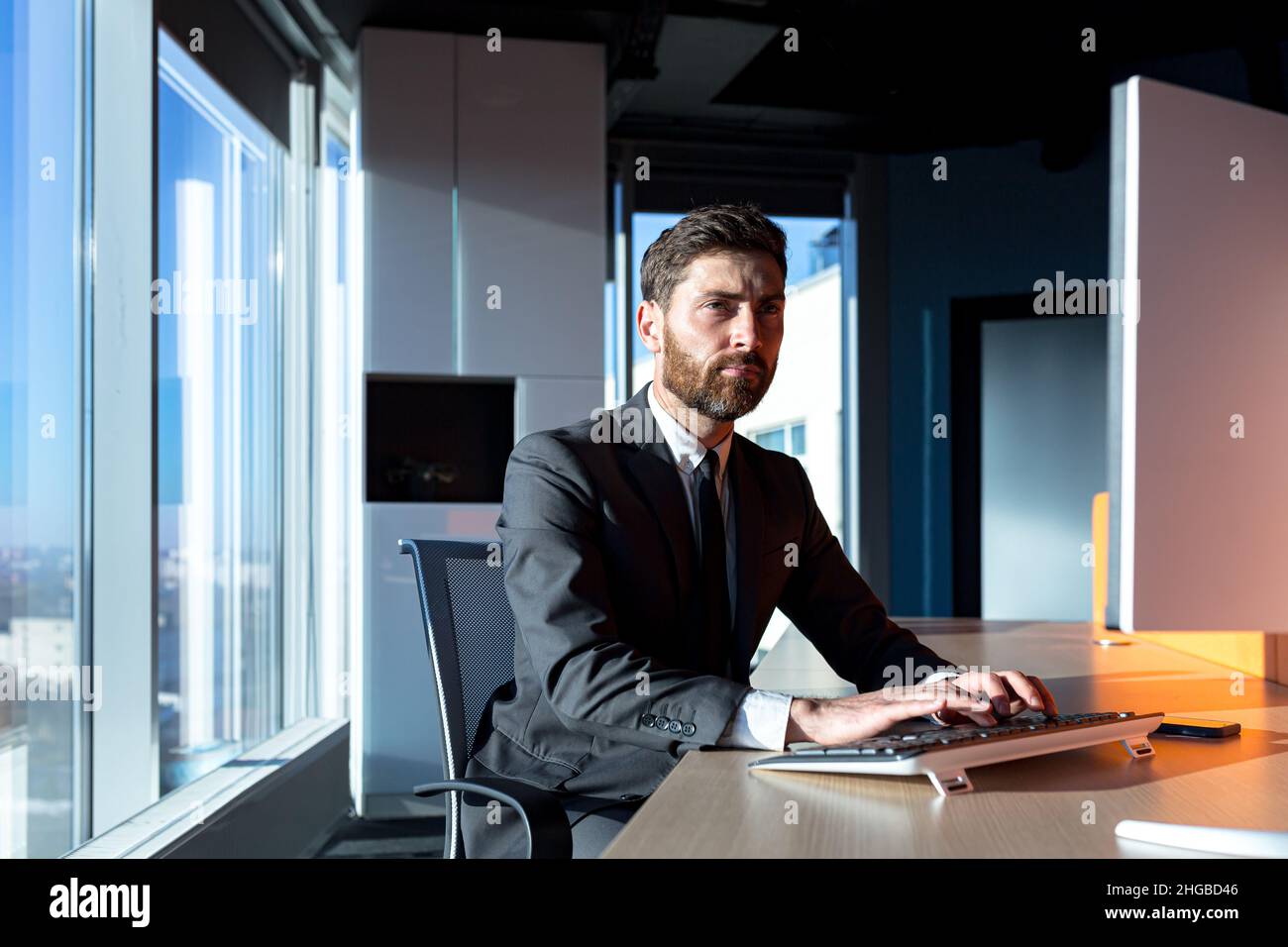 Focused broker working at computer in marvelous office by the window ...