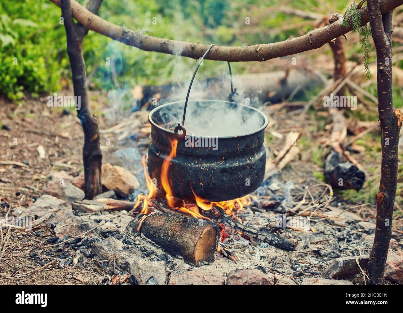 Cooking in field conditions, boiling pot at the campfire on picnic ...
