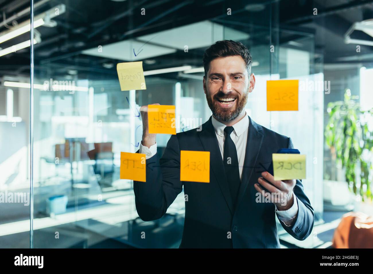 Portrait of a successful businessman near a glass board with tasks, the ...