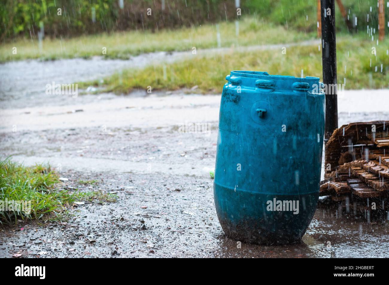 blue trash can placed in the middle of a dirt road in a poor ...