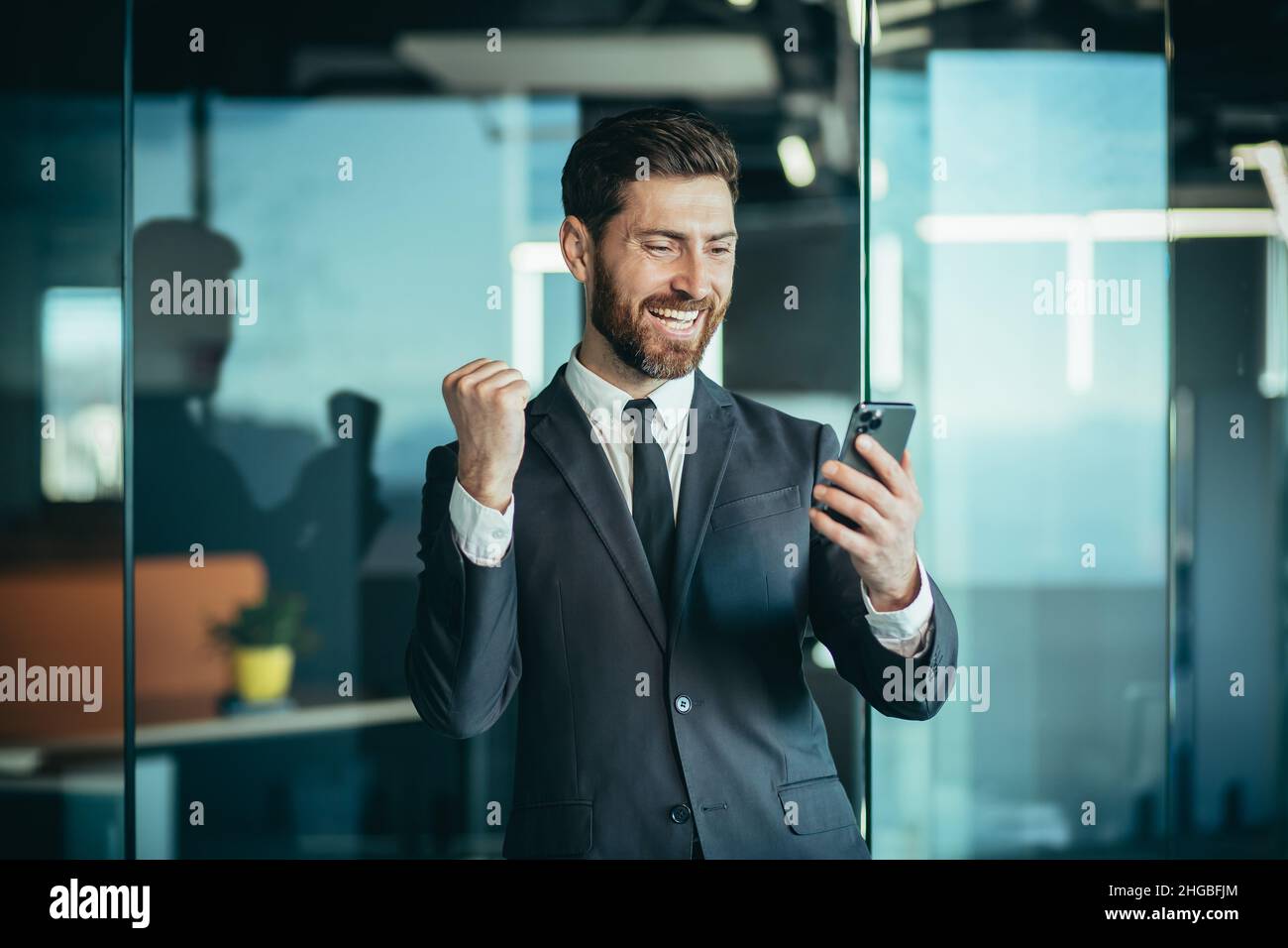 Happy employee looking at phone screen, rejoices and smiles got good ...