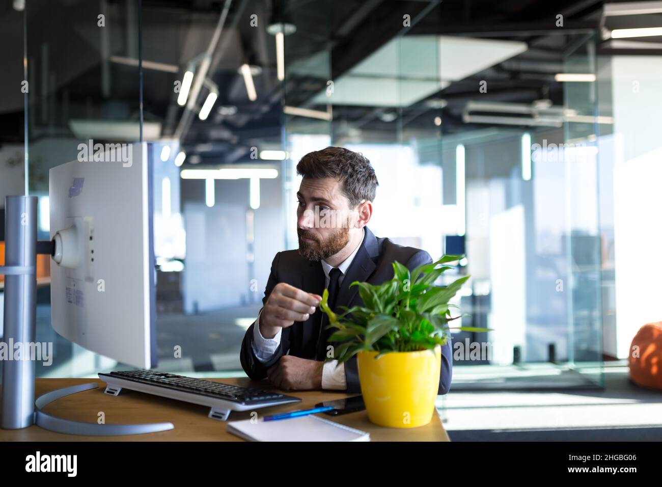 sad and thoughtful man sitting at a desk in the office at the computer ...