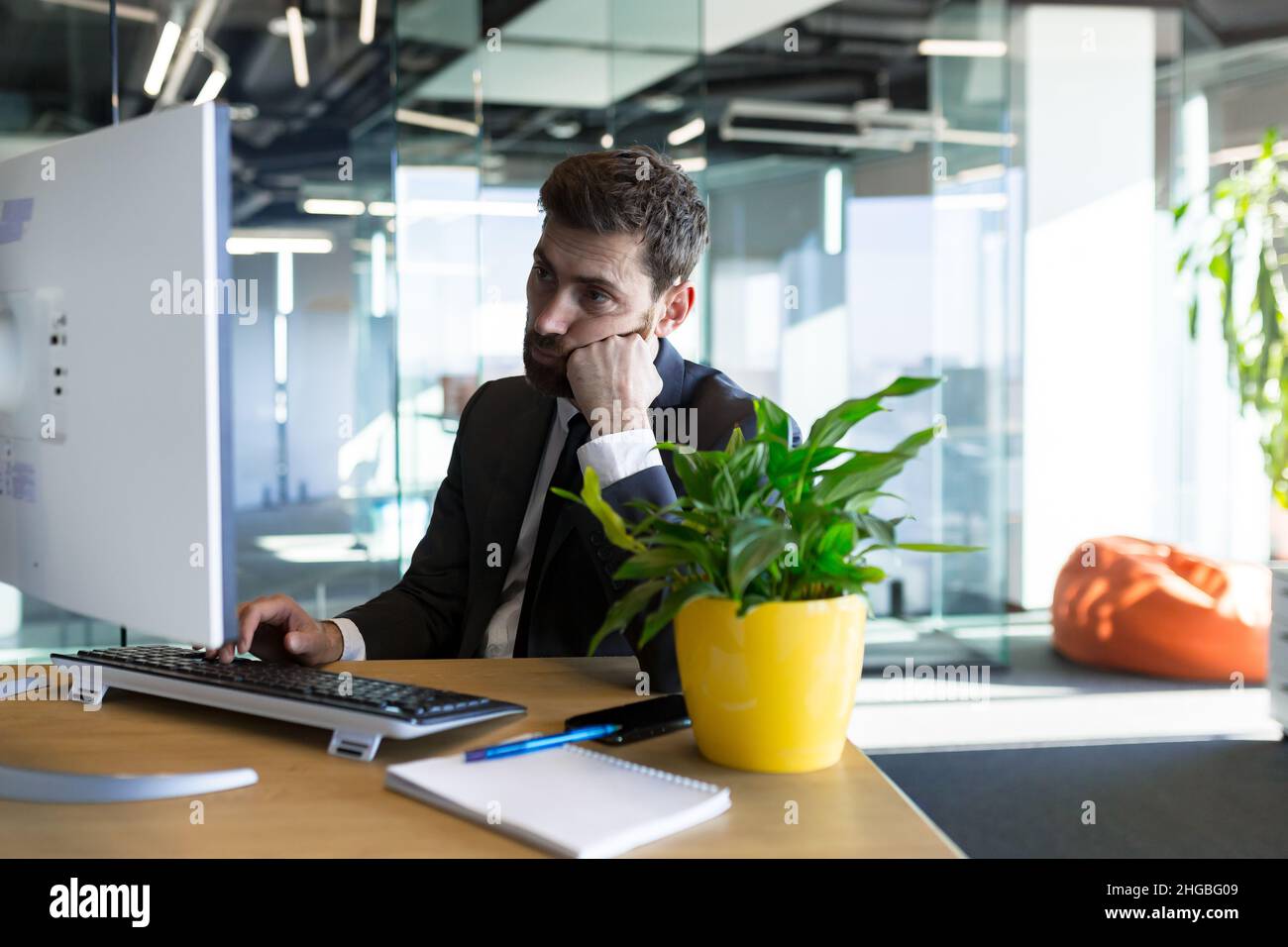 sad and thoughtful man sitting at a desk in the office at the computer ...