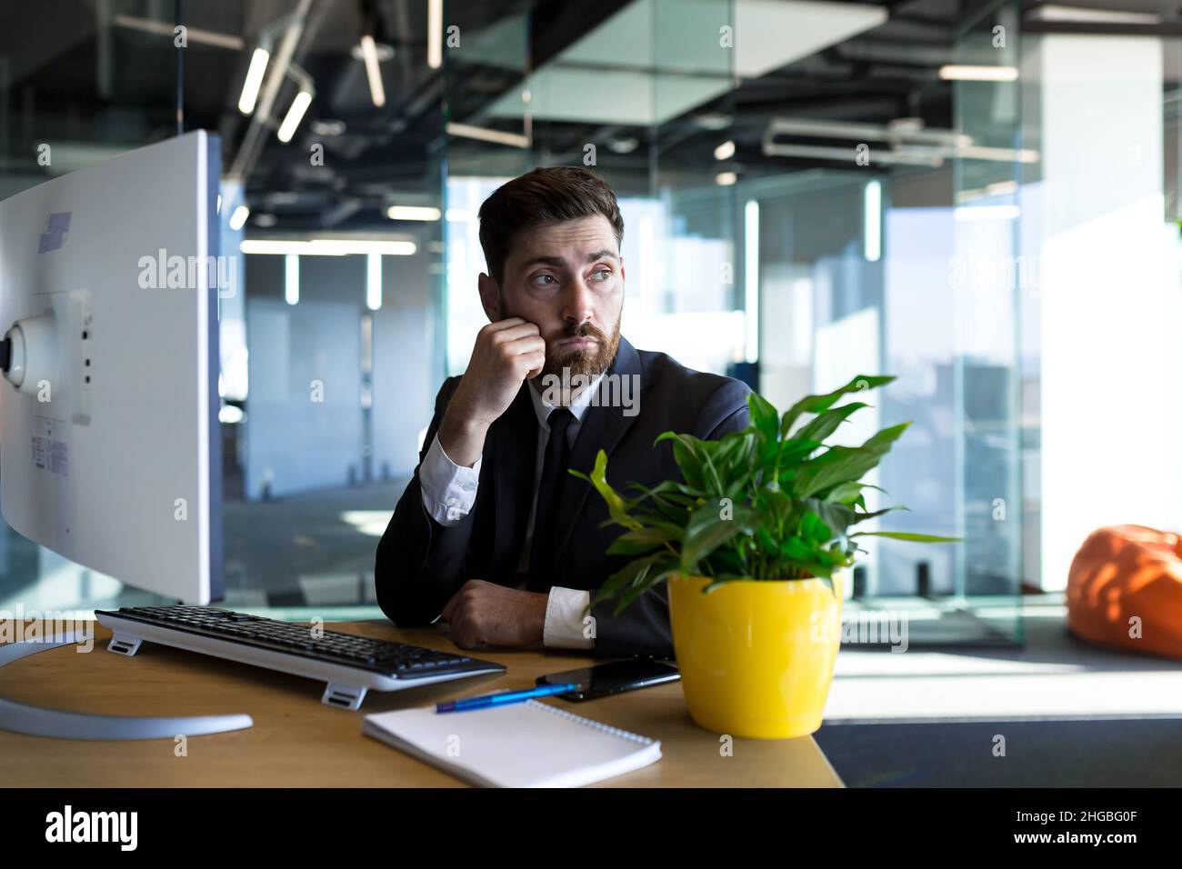 sad and thoughtful man sitting at a desk in the office at the computer ...