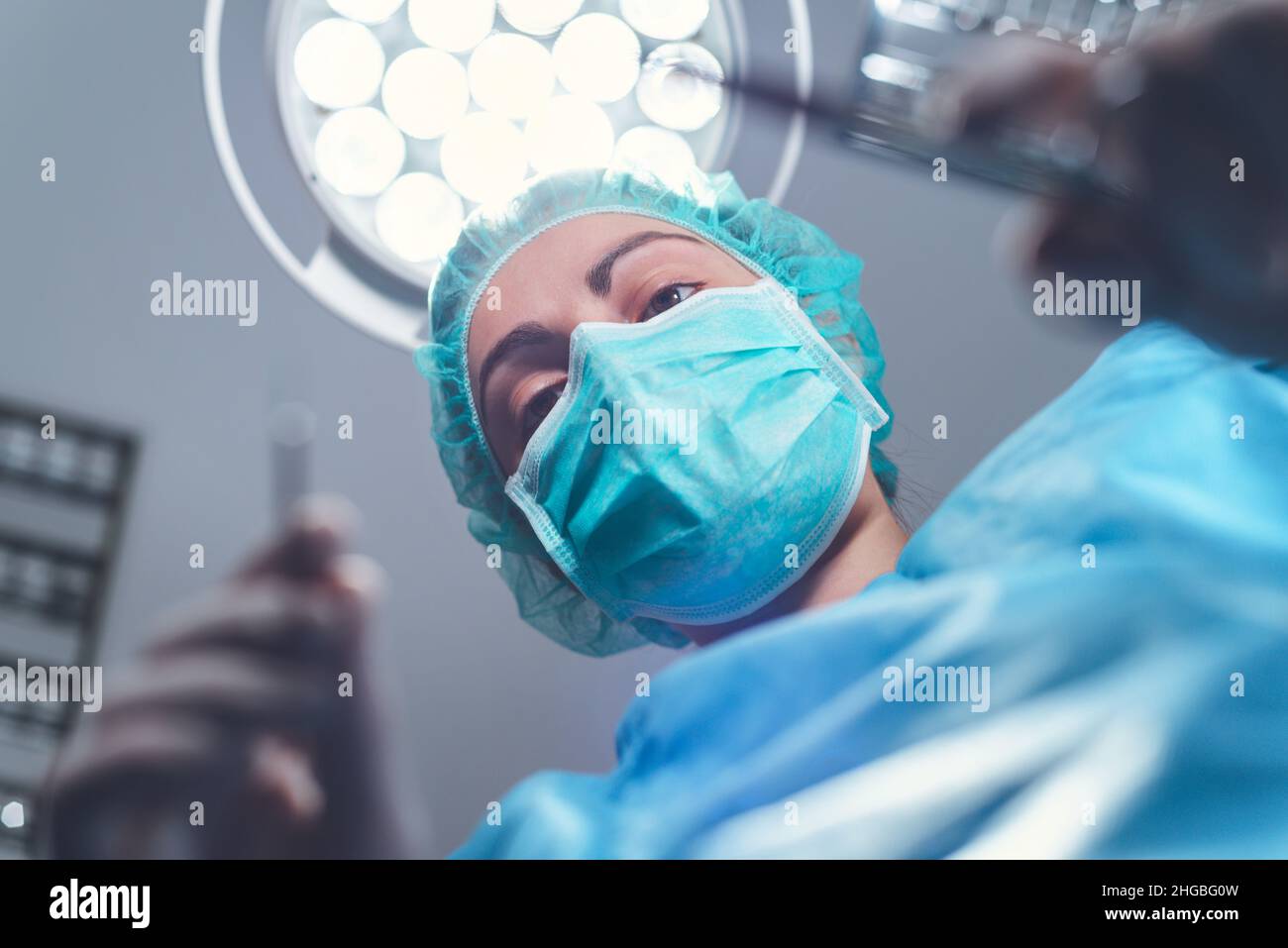 From below woman surgeon in medical uniform using professional tools ...
