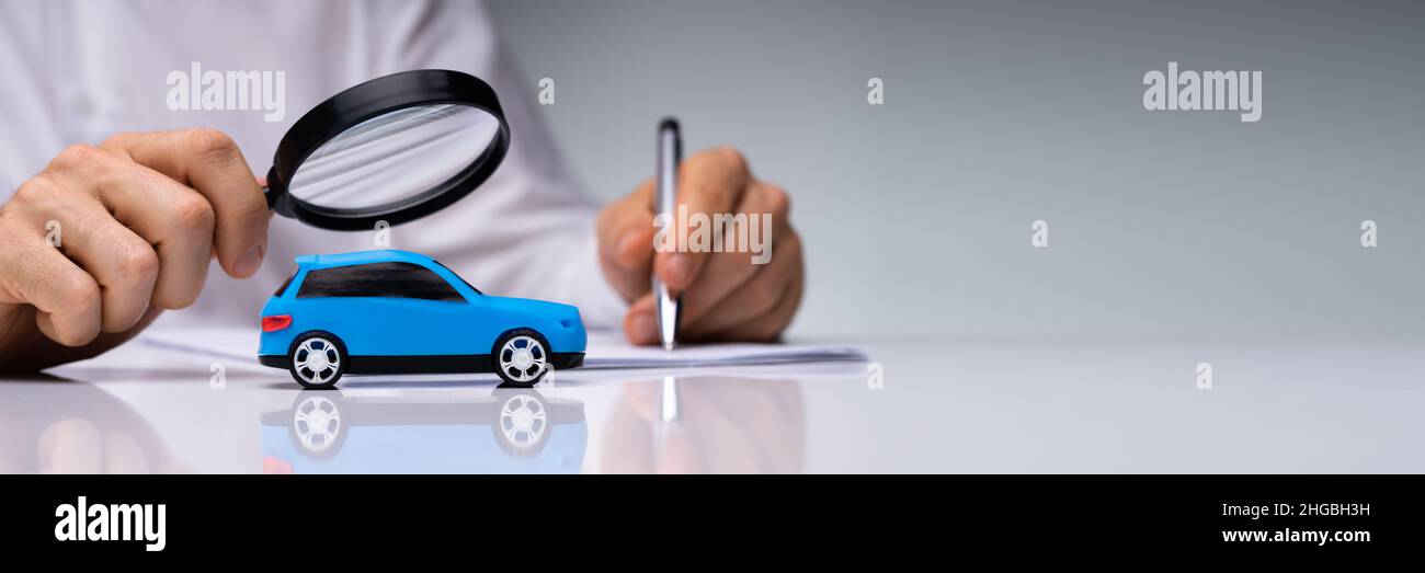 Person Scrutinizing A Car Model Using Magnifying Glass On Desk Stock ...