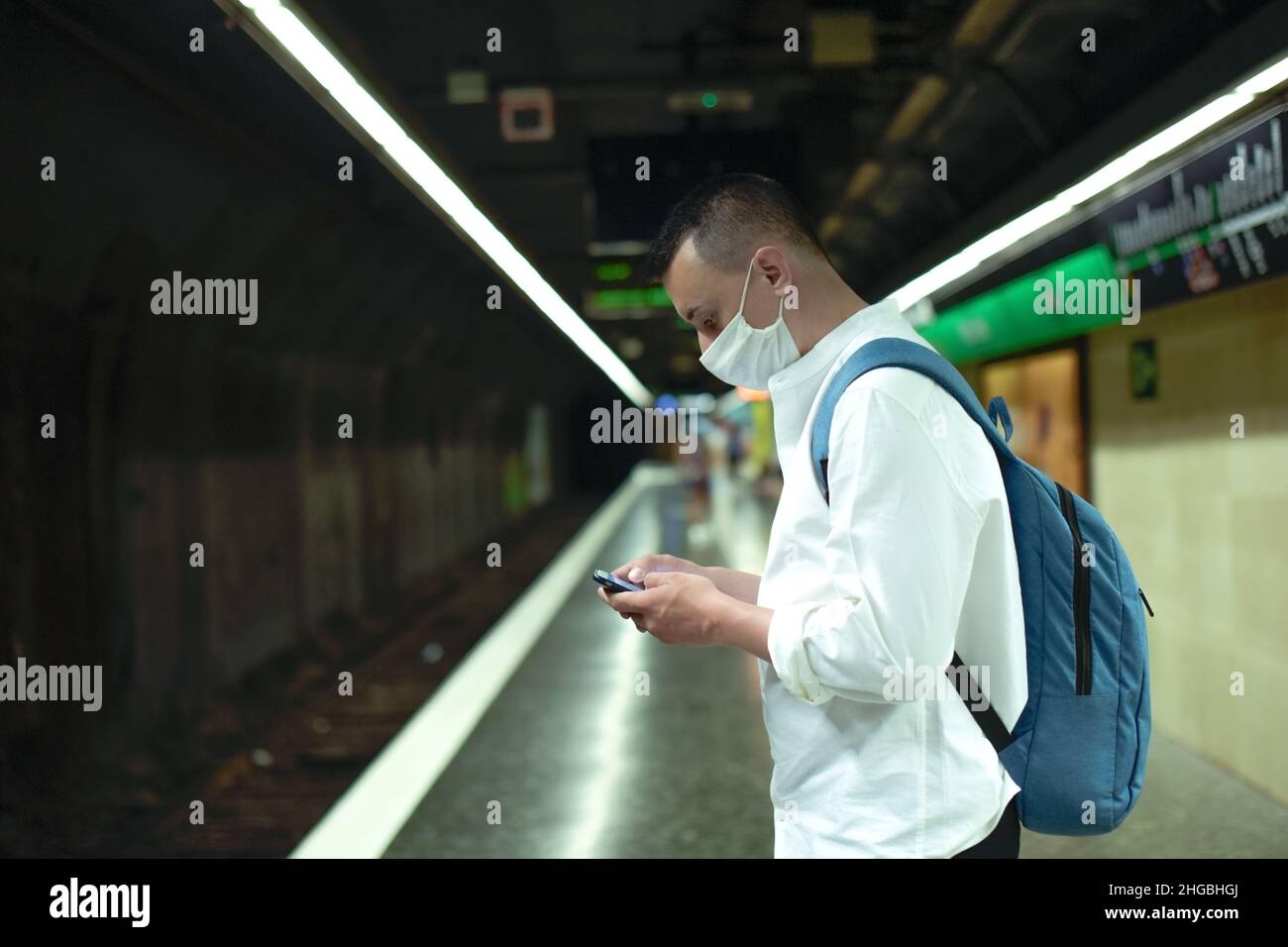 A masked man stands in the subway with a phone in his hands. Actions ...
