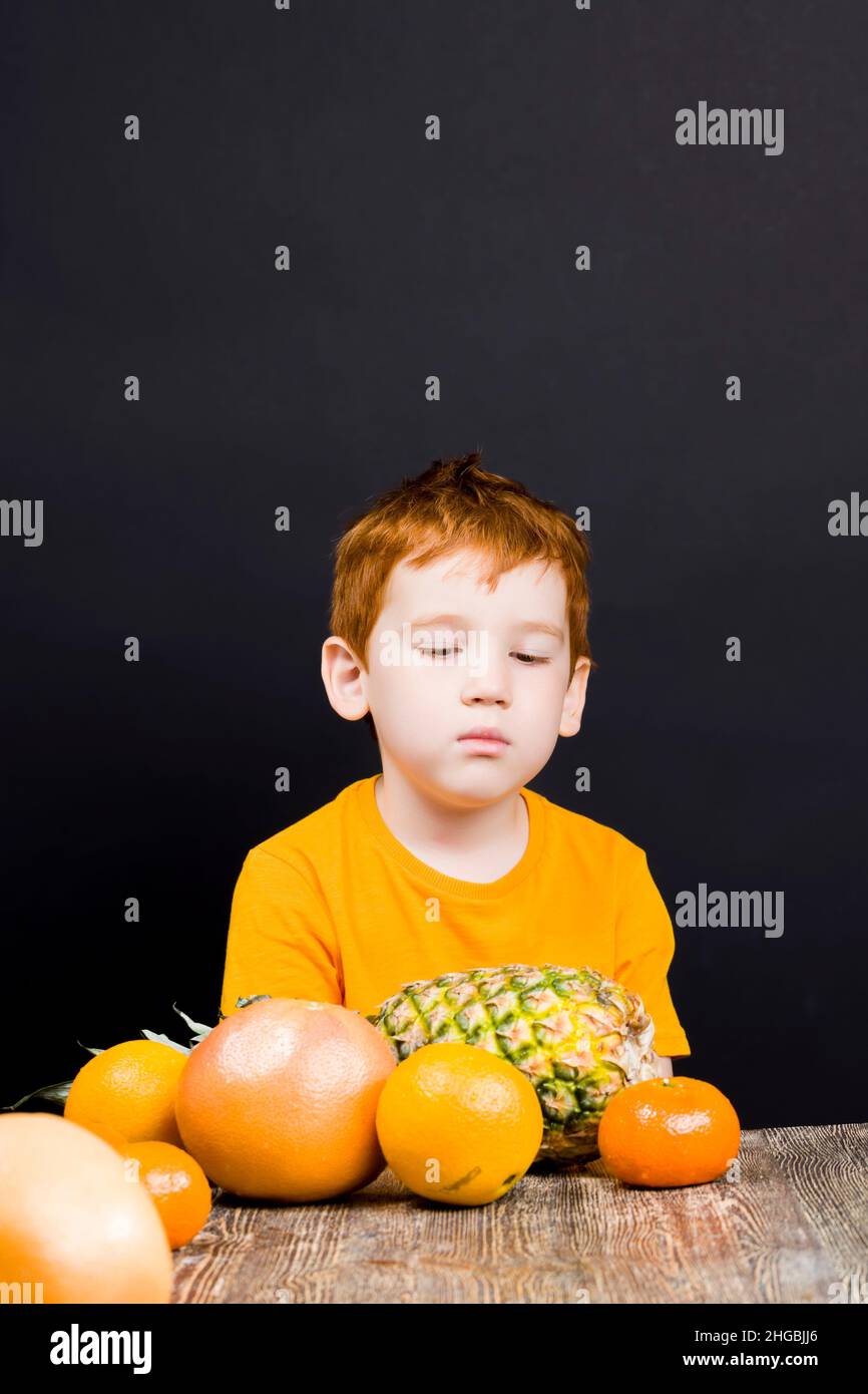 a beautiful pleasant red haired boy with citrus fruits from which you ...