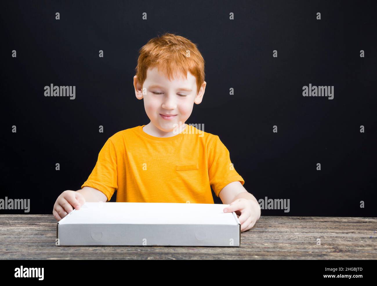 the boy at the table eats pizza, the child's box which contains the ...