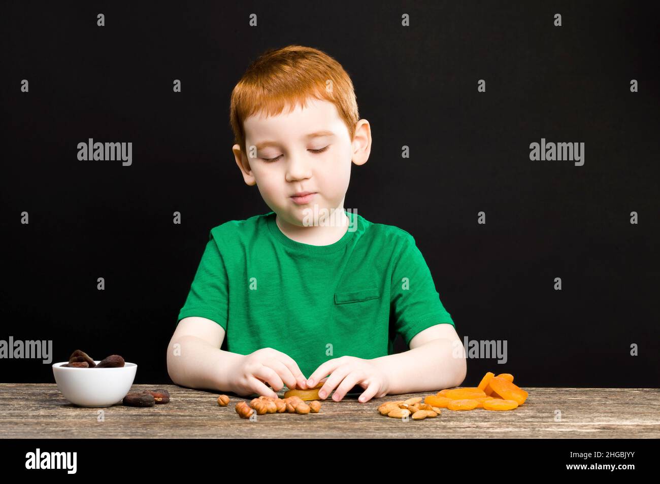 a boy sits thoughtfully next to dried fruits, close-up and portrait of ...