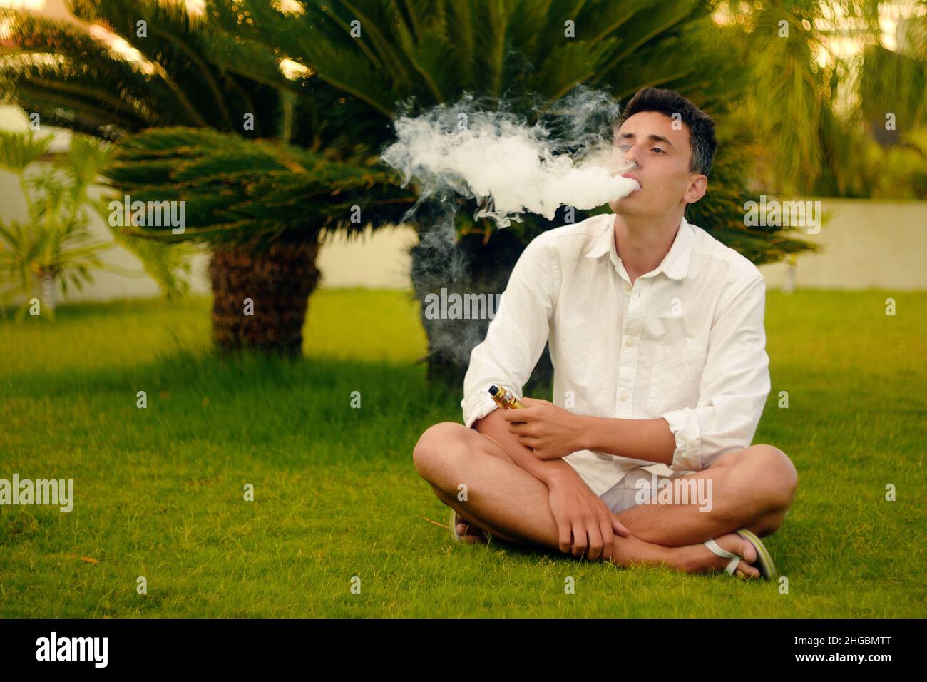 A vape man on vacation, under a palm tree. Rest, smoking, nicotine ...