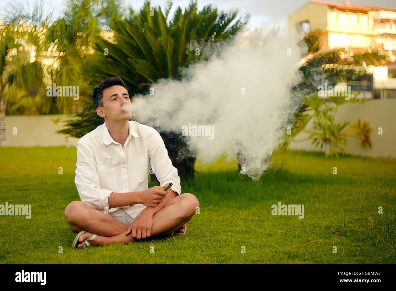 A vape man on vacation, under a palm tree. Rest, smoking, nicotine ...