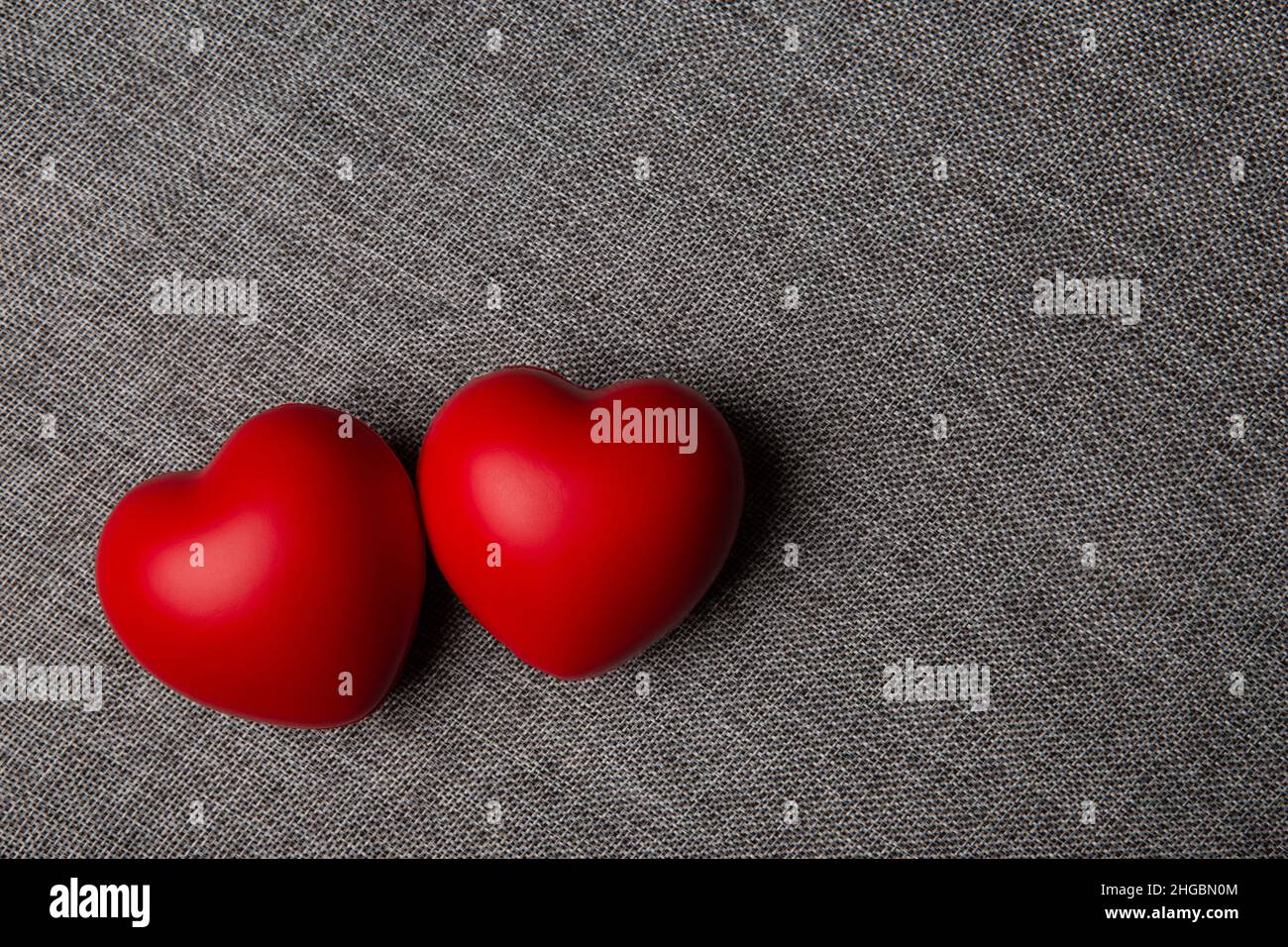 two large red hearts on a textile background Stock Photo - Alamy