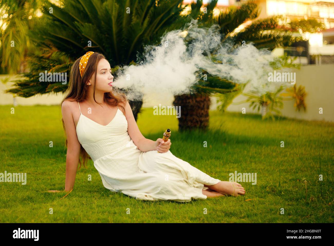 A vape woman on vacation, under a palm tree. Rest, smoking, nicotine ...