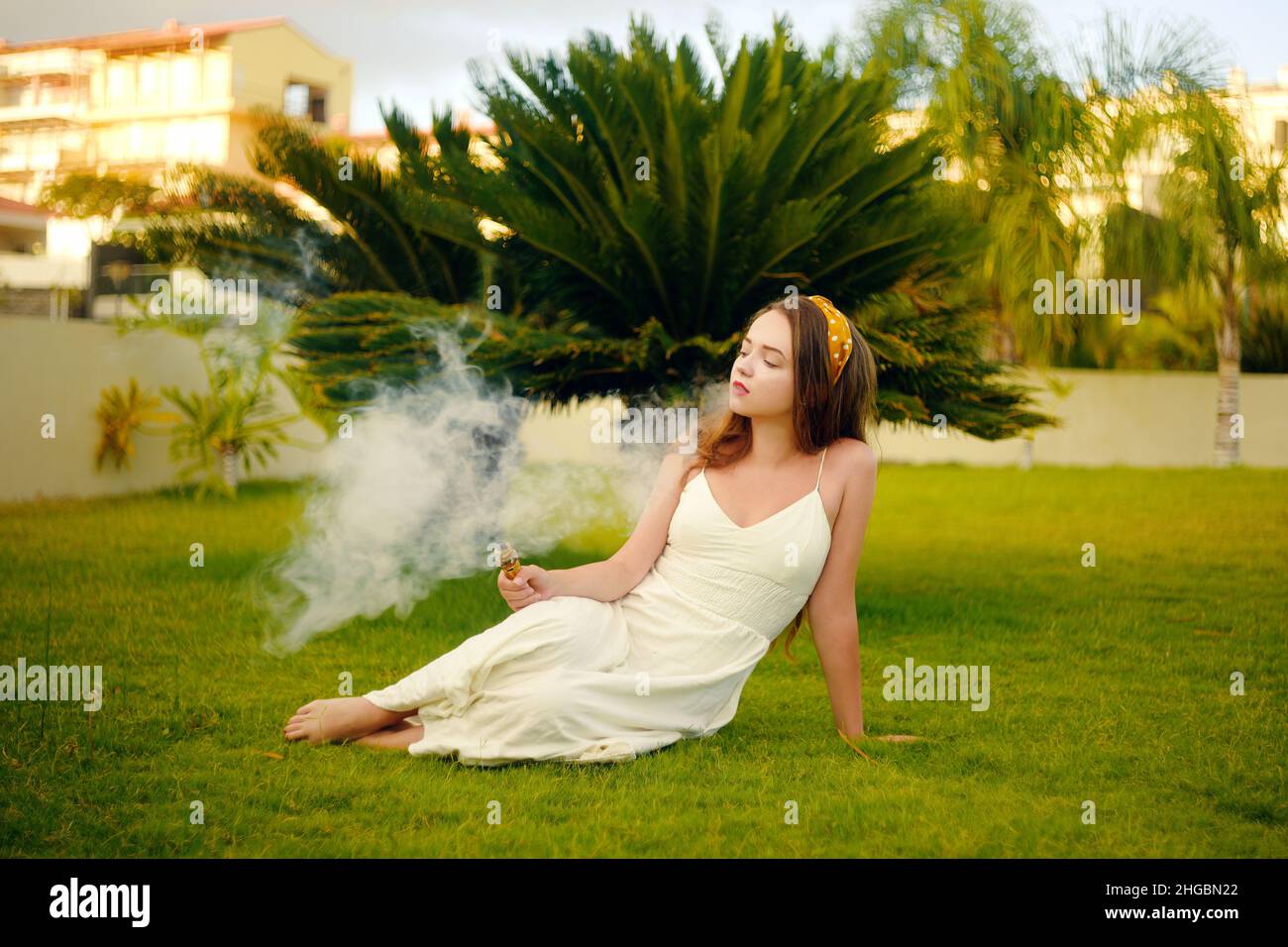 A vape woman on vacation, under a palm tree. Rest, smoking, nicotine ...