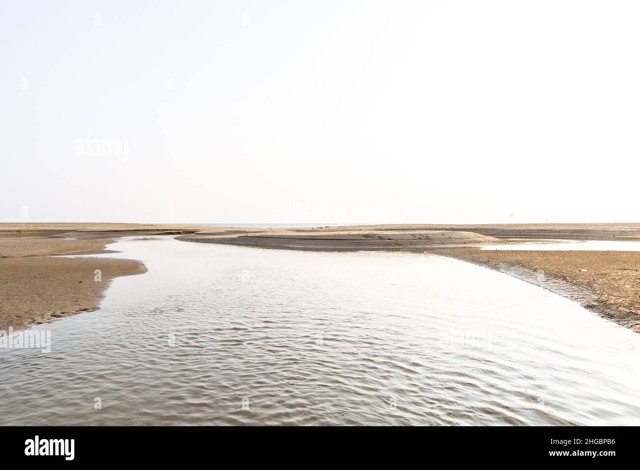 View of the river flowing through the beach and meeting the sea forming ...