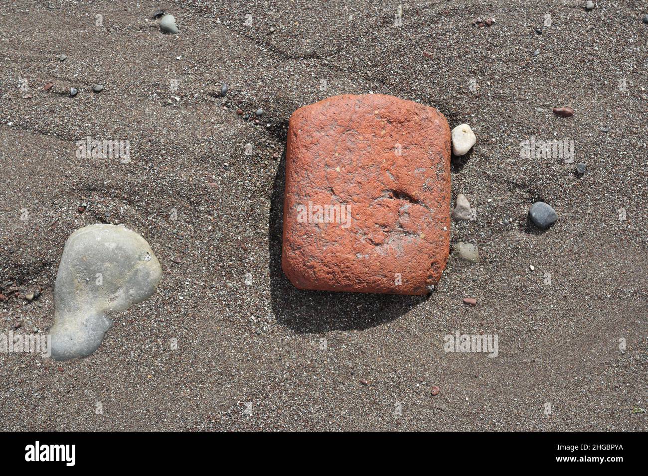 A piece of red brick on a sandy beach, abstract natural still life ...