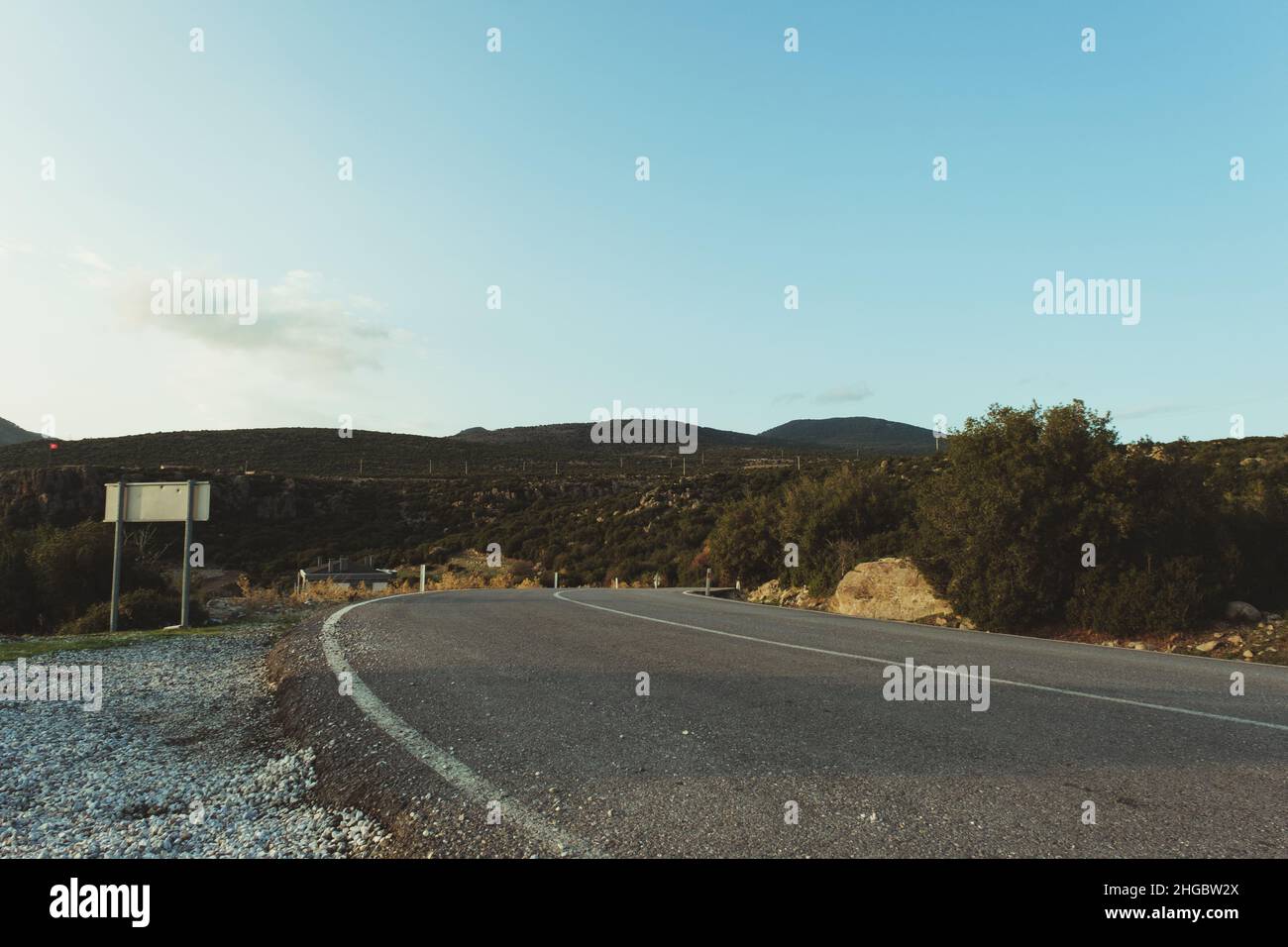 Bending one lane road with trees and bushes Stock Photo - Alamy