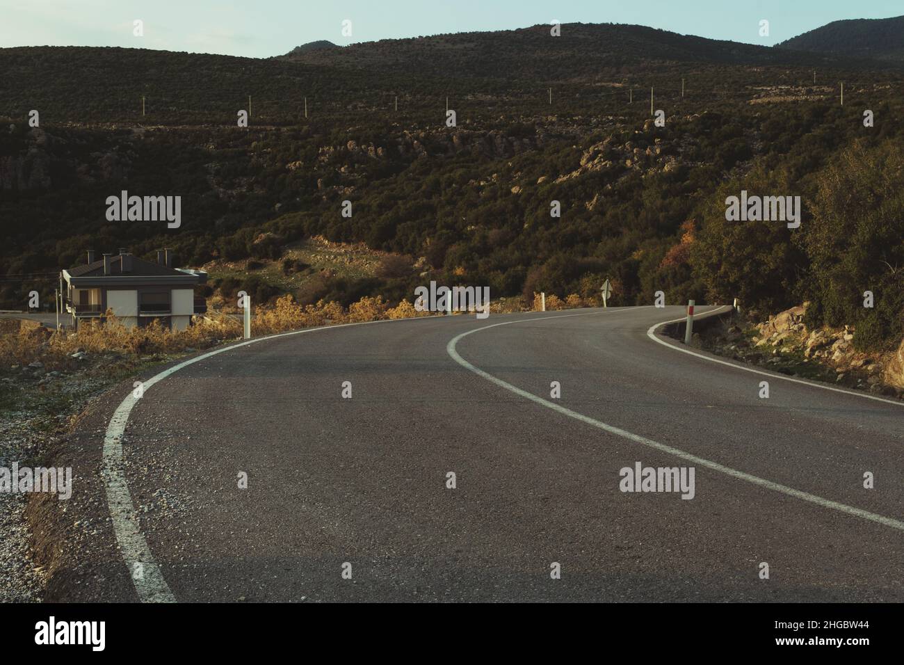 Bending one lane road with trees and bushes Stock Photo - Alamy