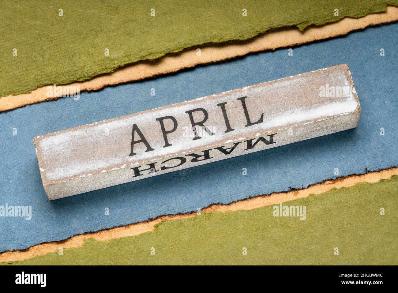 April text on grunge wooden block against handmade rag paper in blue ...
